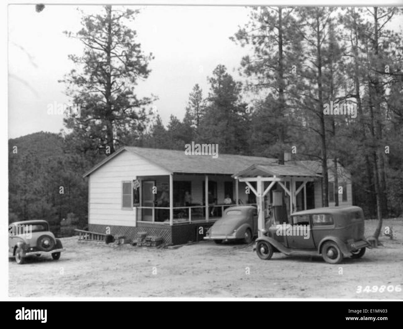 A black and white image depicting historic cars in a forested area ...