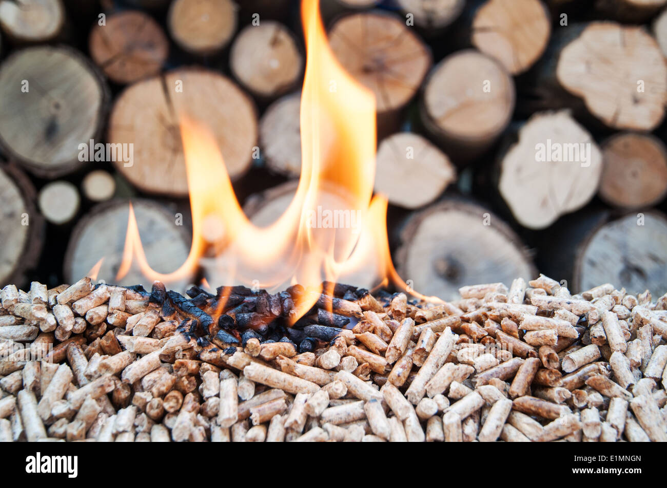 Pine pellets in flames- behind flames are fire wood Stock Photo - Alamy