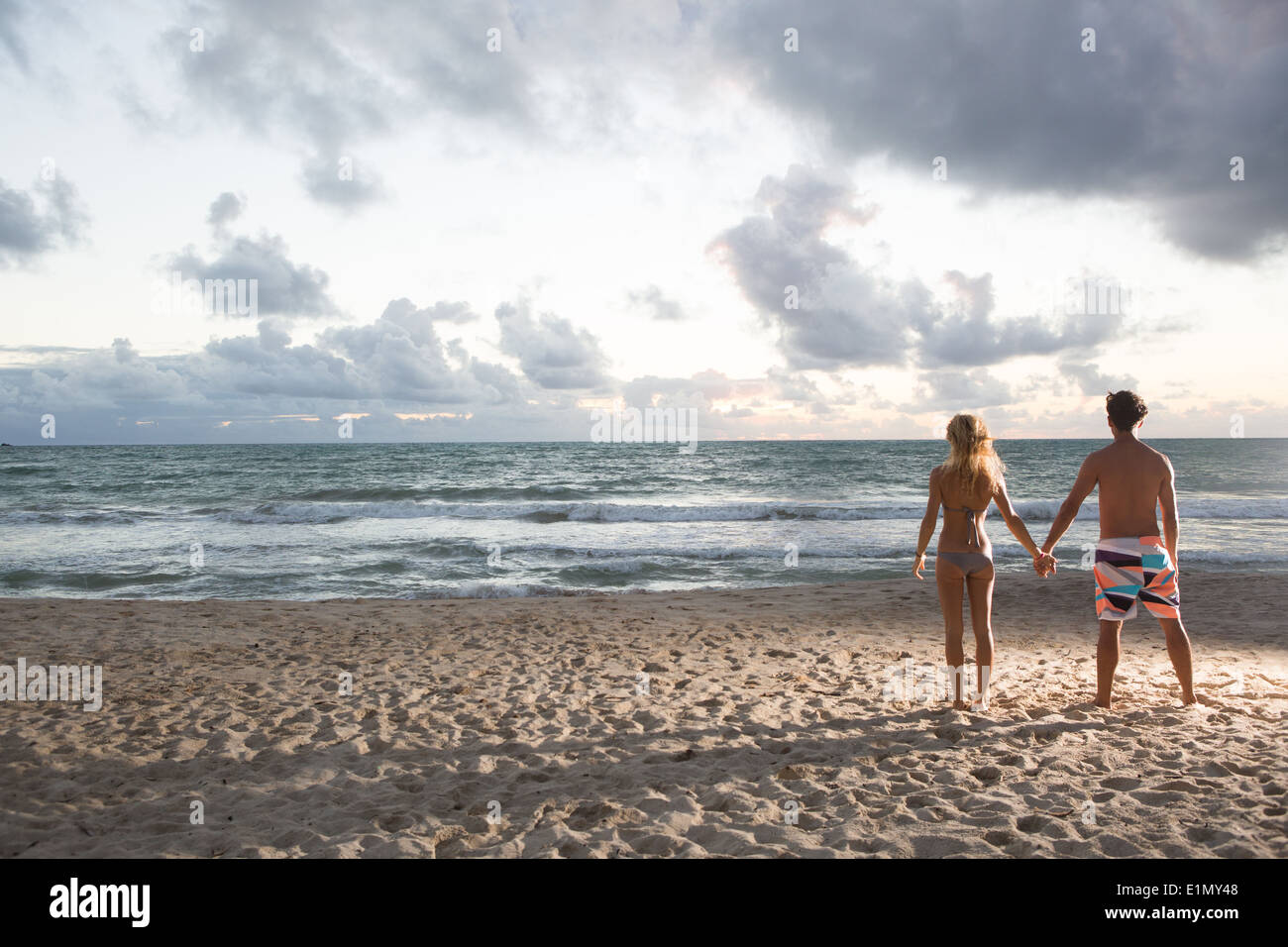A couple holds hands while watching the sunrise Stock Photo - Alamy