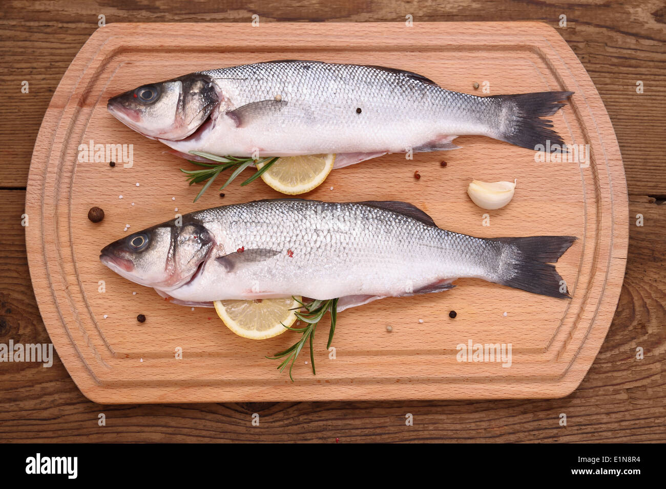 Two fresh moronidae fish on cutting board with ingredients, top view ...