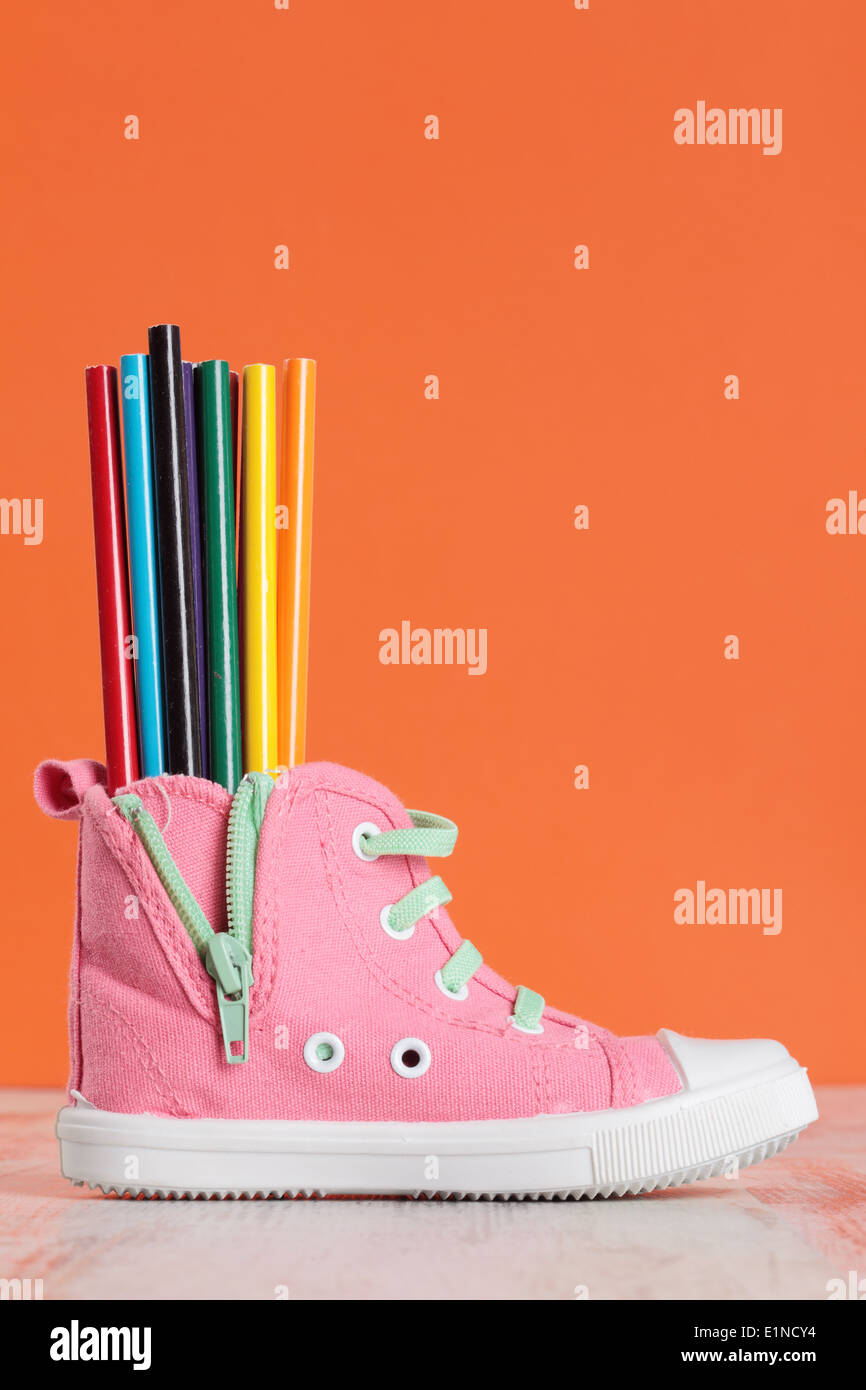 child shoe with colored pencils on an orange background Stock Photo - Alamy