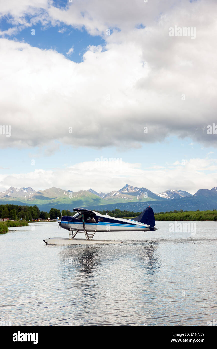 A bush plane performs take off in Alaska with Chugach Mountains in the ...