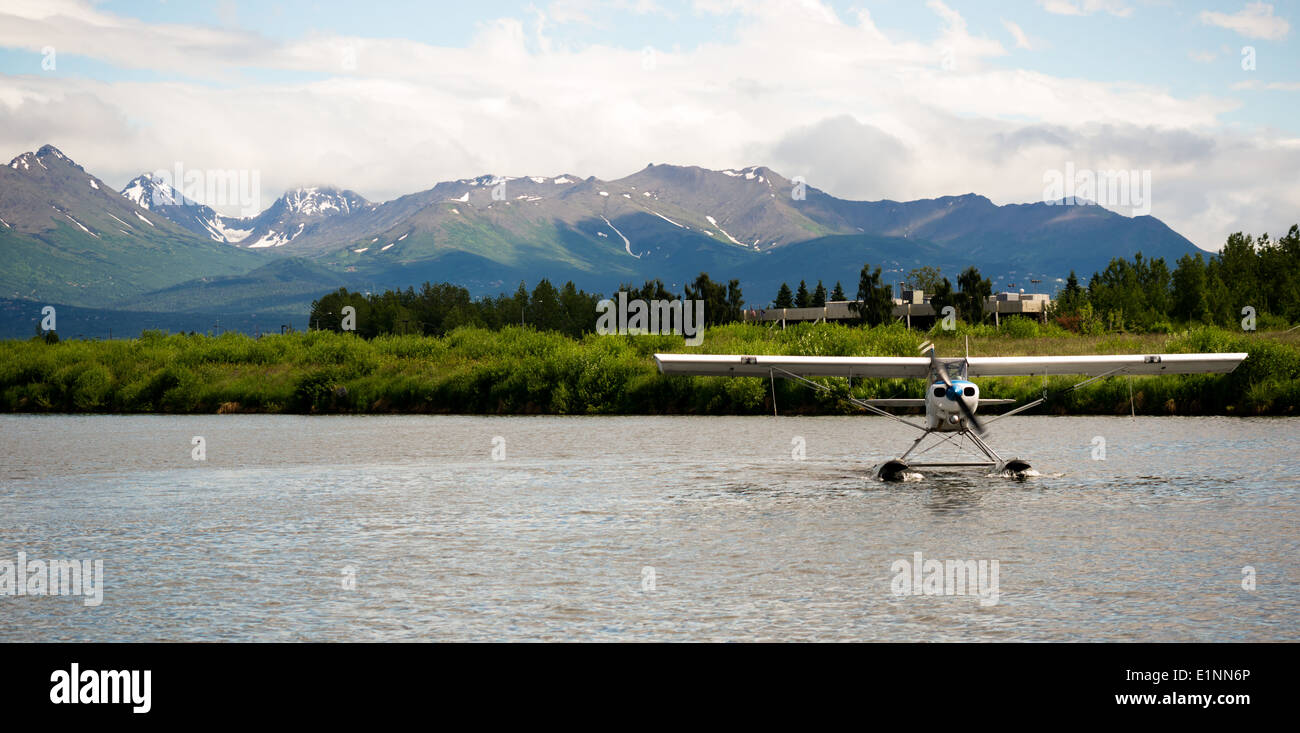 A bush plane performs take off in Alaska with Chugach Mountains in the ...