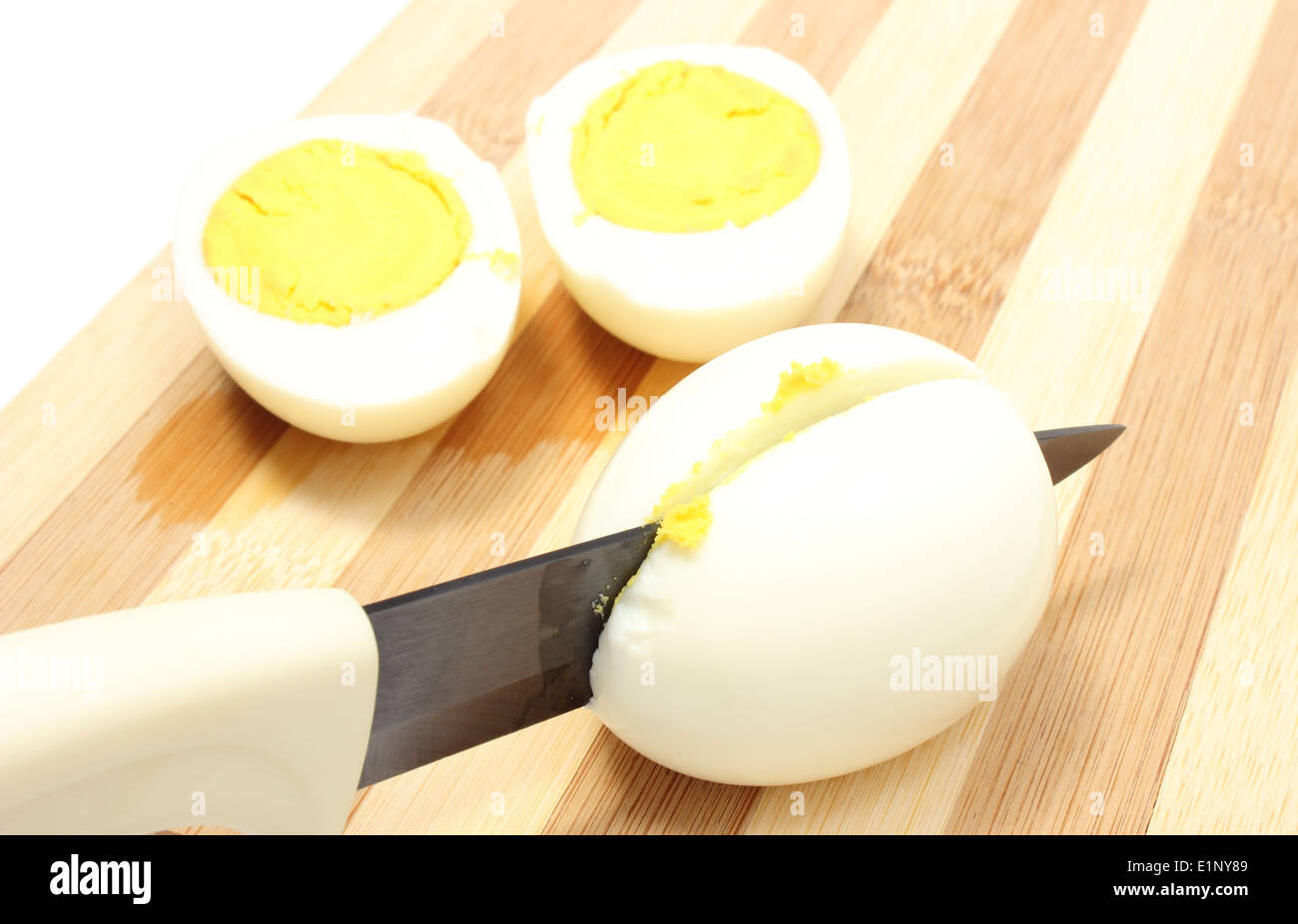 Halves of eggs with ceramic knife, sliced egg with knife on wooden ...