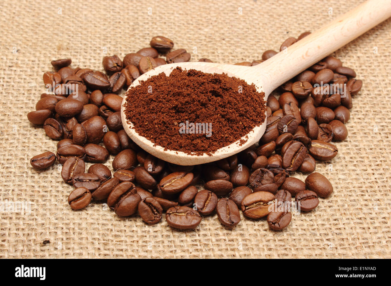 Ground coffee on wooden scoop lying on heap of coffee beans, coffee ...