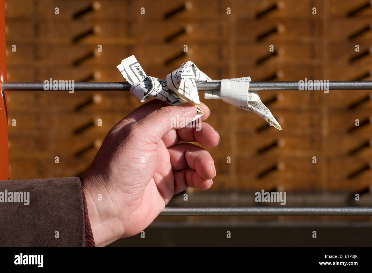 Tying Buddhist omikuji, fortunes written on slips of paper, to a rack ...