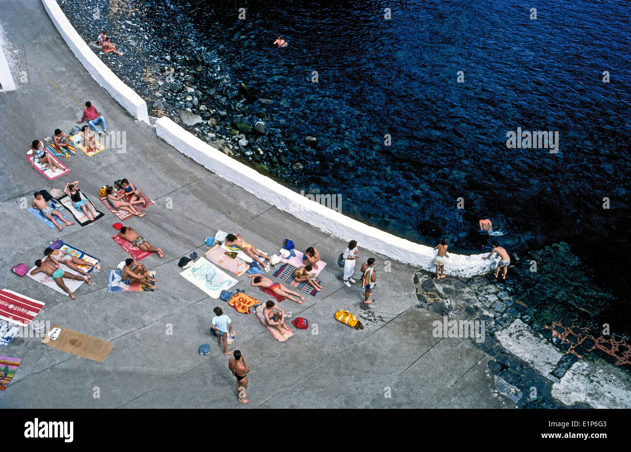 Sunbathers relax on their towels by the waterfront in the historic city ...