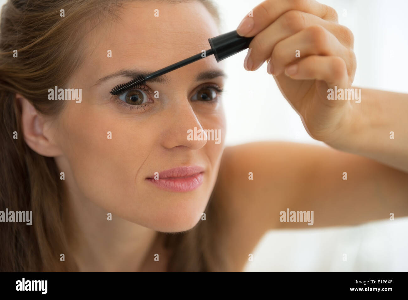Portrait of young woman applying mascara Stock Photo - Alamy