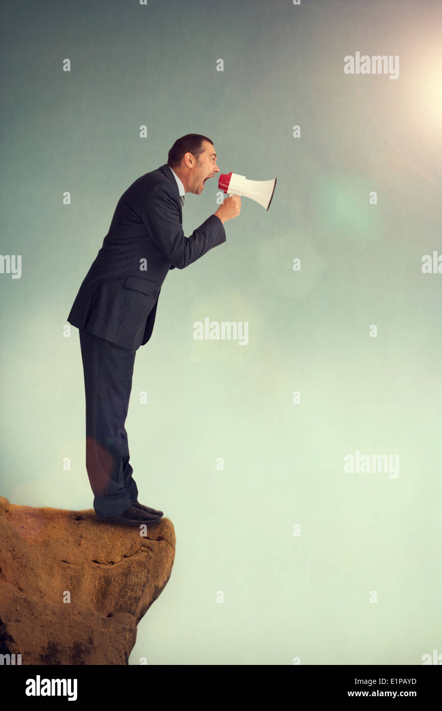 businessman with loudhailer on the edge of a cliff shouting Stock Photo ...