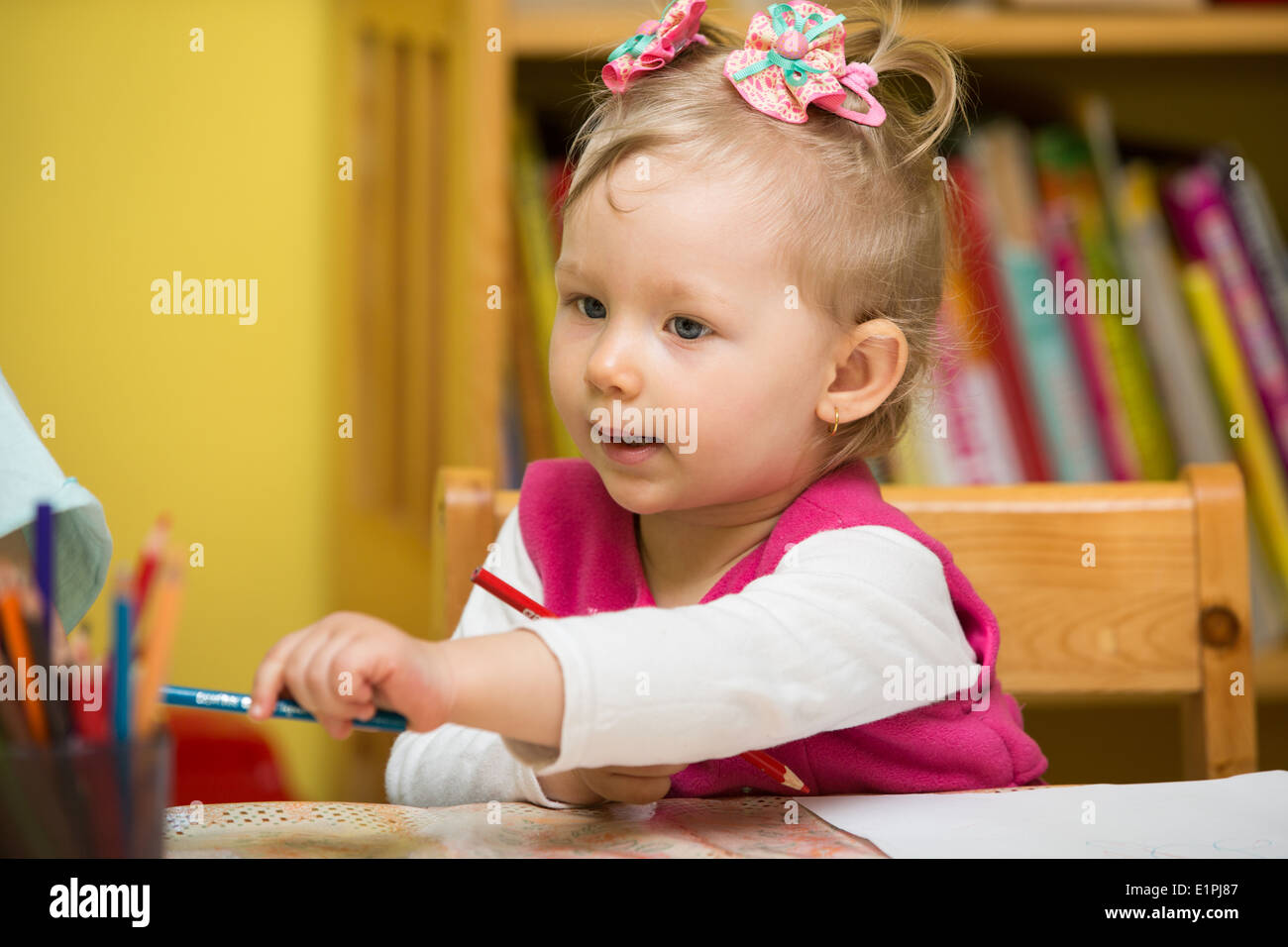 Cute child girl drawing with colorful pencils in preschool at the table ...