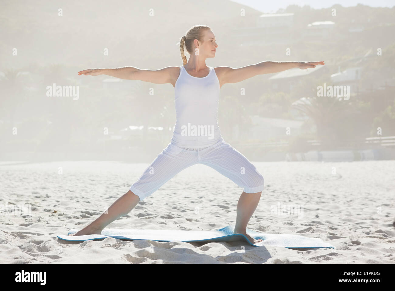 Calm woman standing in warrior pose on beach Stock Photo - Alamy