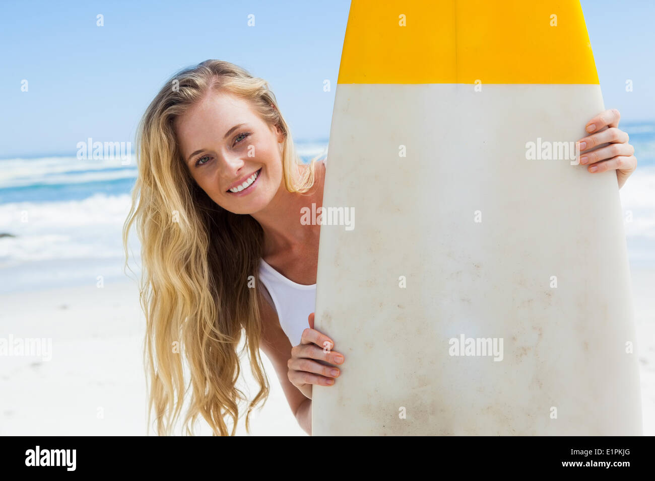 Blonde surfer holding her board smiling at camera Stock Photo - Alamy