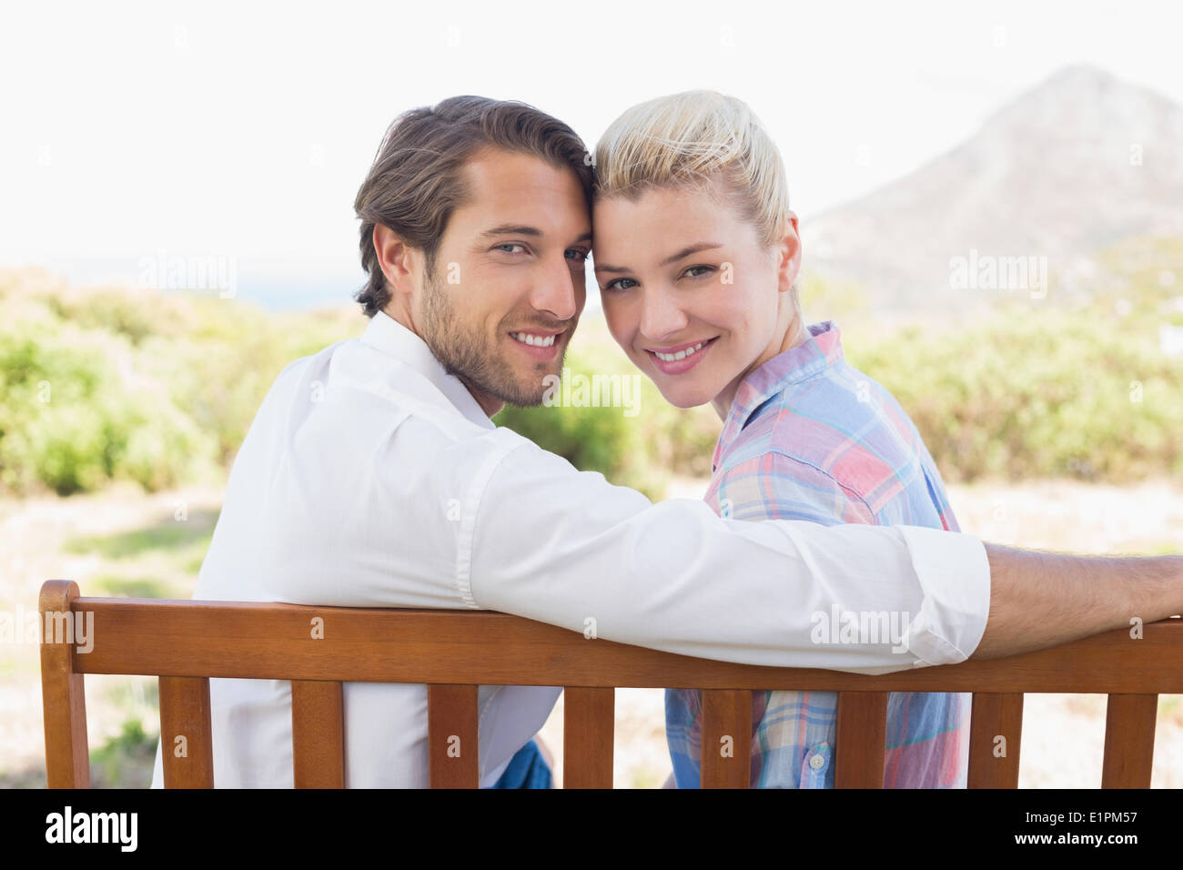 Cute couple sitting on bench together smiling at camera Stock Photo - Alamy