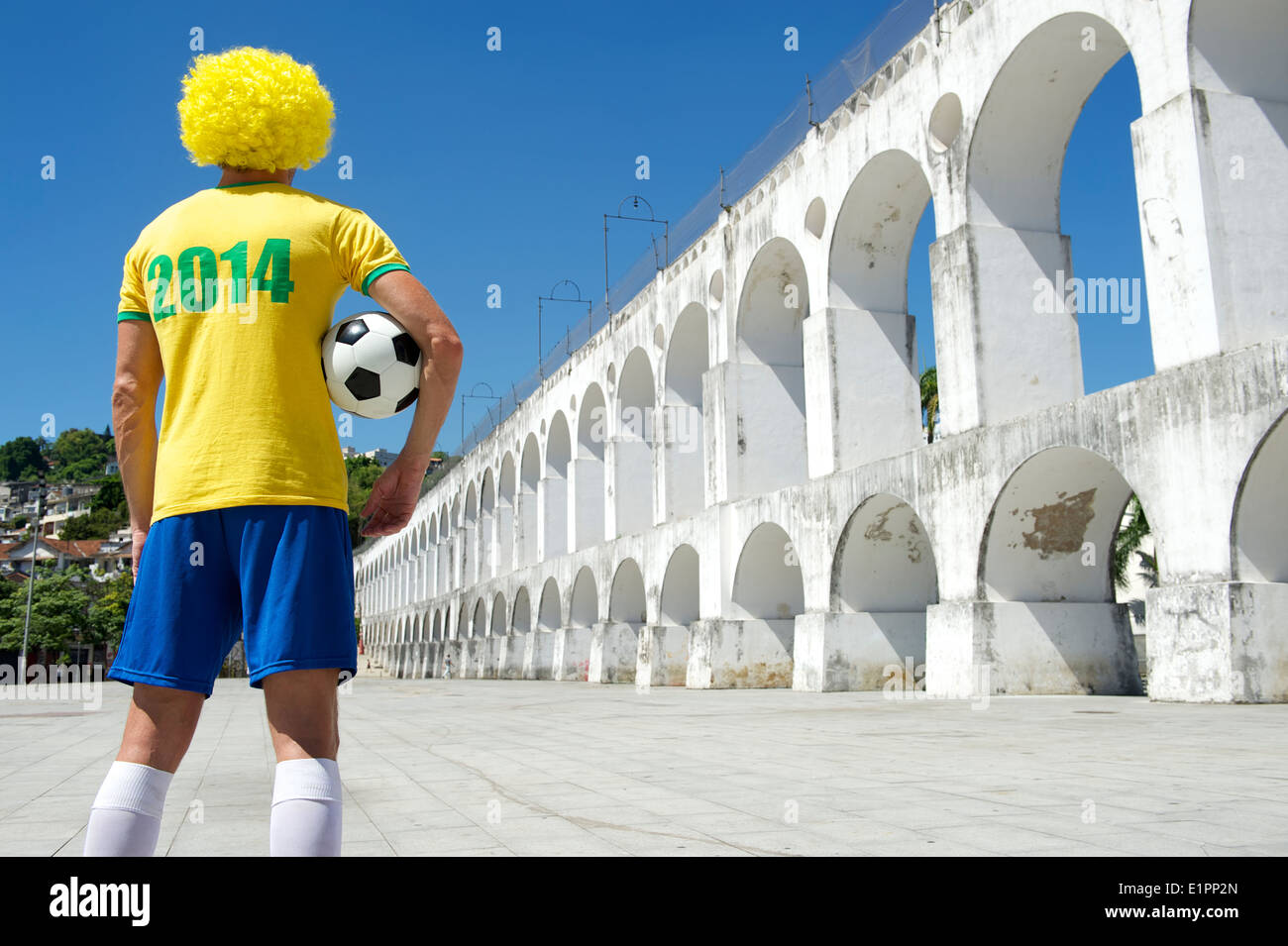 Brazilian football player with yellow afro wig holding soccer ball ...