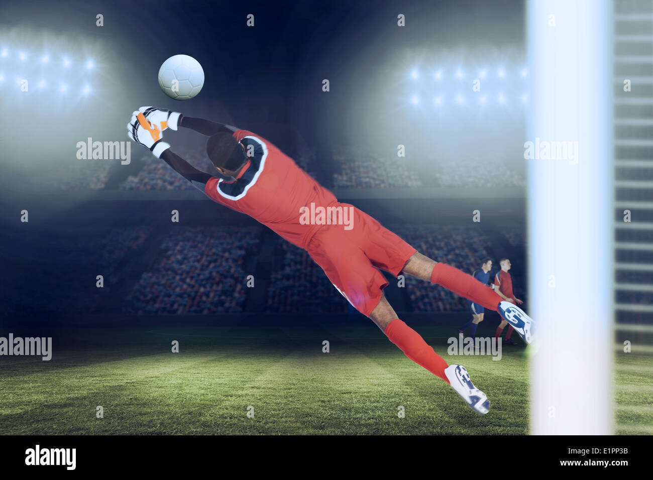 Composite image of goalkeeper in red making a save Stock Photo - Alamy