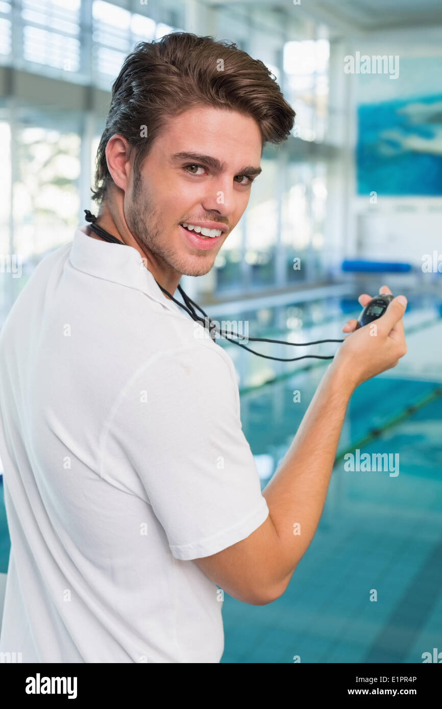 Swimming coach standing by the pool looking at stopwatch Stock Photo ...