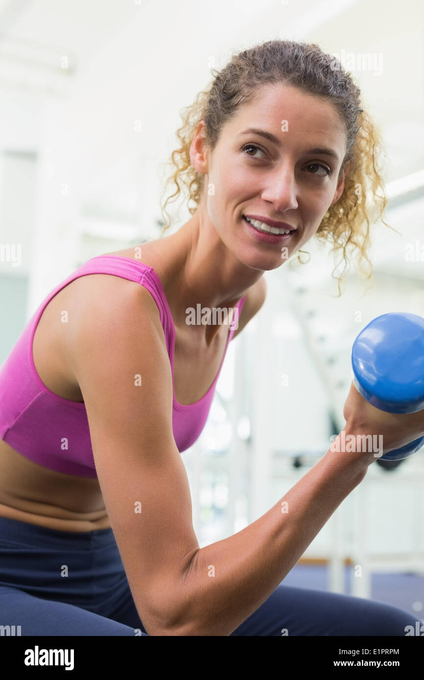Pretty fit woman lifting blue dumbbell sitting on bench Stock Photo - Alamy