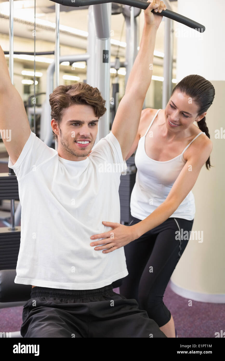 Fit man using weights machine for arms with his trainer Stock Photo - Alamy