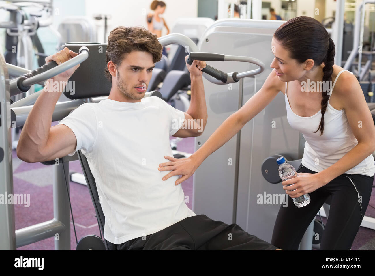 Fit man using weights machine for arms with his trainer Stock Photo - Alamy