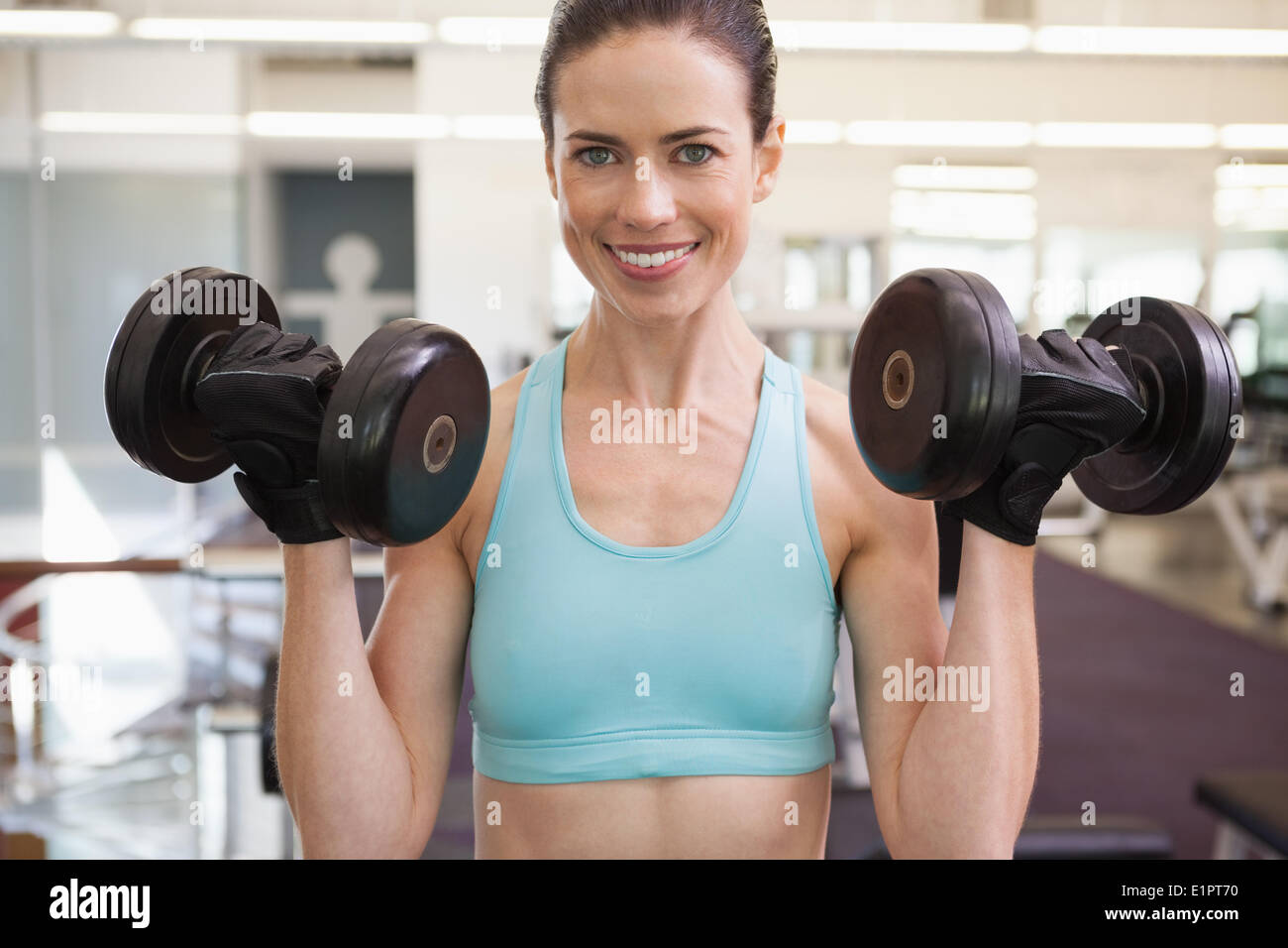 Smiling woman lifting heavy dumbbells Stock Photo - Alamy