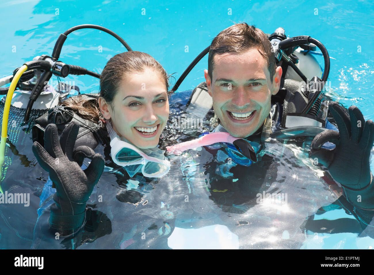 Smiling couple on scuba training in swimming pool showing ok gesture ...