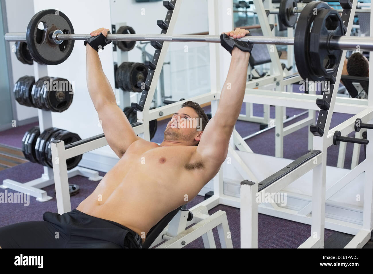 Shirtless bodybuilder lifting heavy barbell weight lying on bench Stock ...