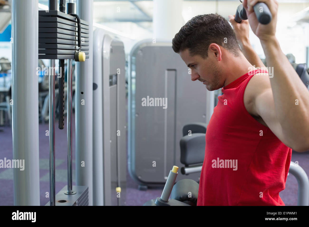 Strong bodybuilder using weight machine for arms Stock Photo - Alamy