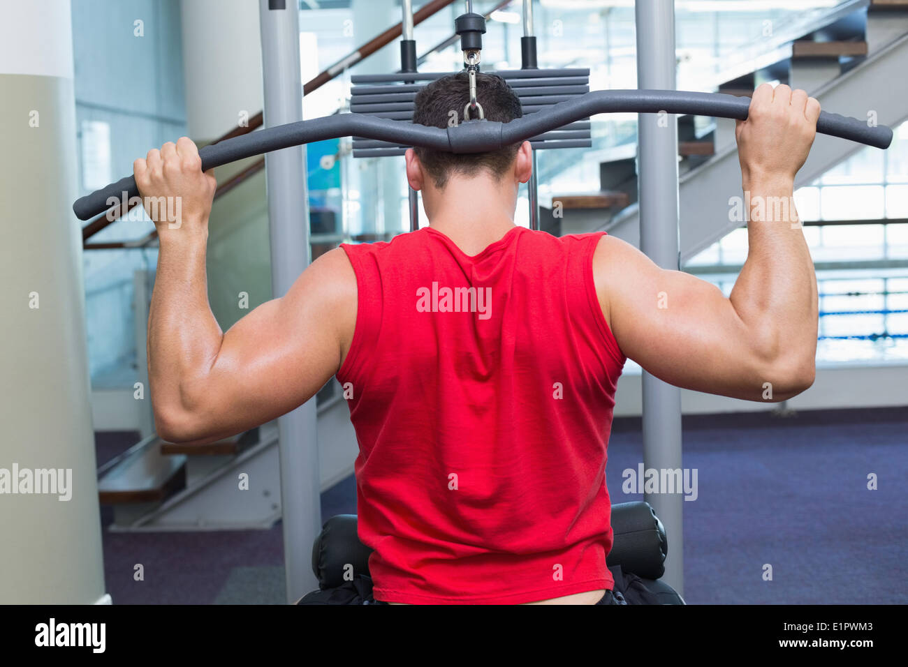 Strong bodybuilder using weight machine for arms Stock Photo - Alamy
