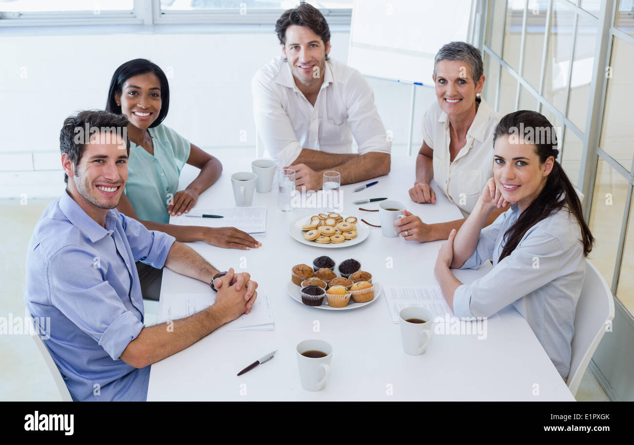 Casual smiling business team having a meeting using laptop in the ...