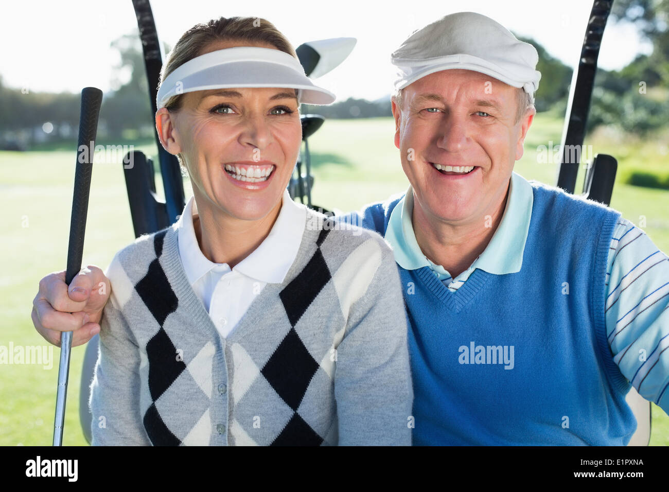Happy golfing couple sitting in golf buggy smiling at camera Stock ...