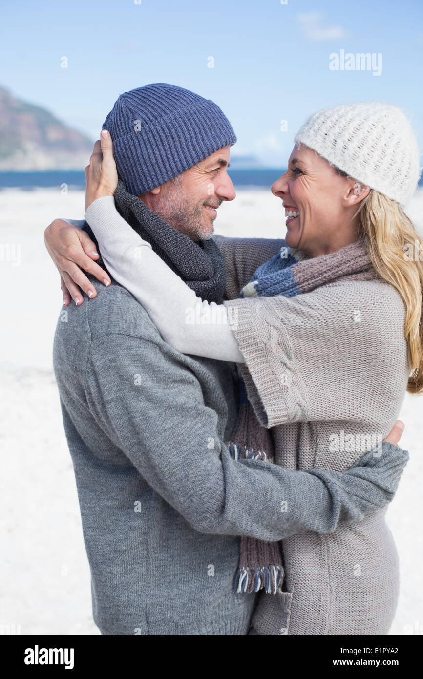 Attractive couple hugging on the beach in warm clothing Stock Photo - Alamy