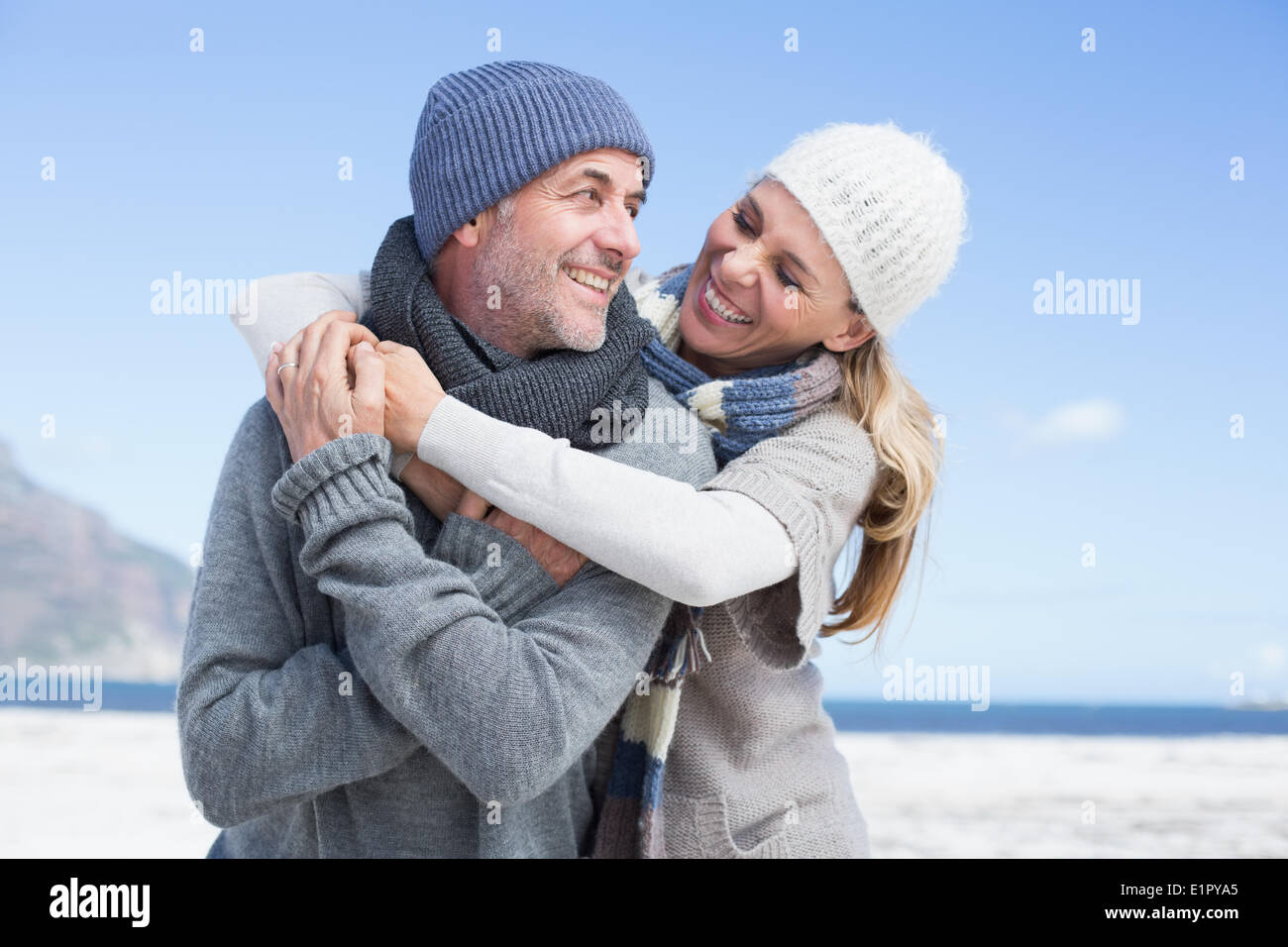 Attractive couple hugging on the beach in warm clothing Stock Photo - Alamy