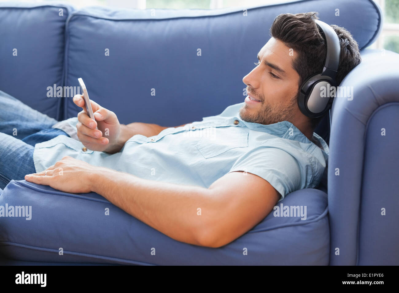 Attractive man lying on the couch listening to music Stock Photo - Alamy