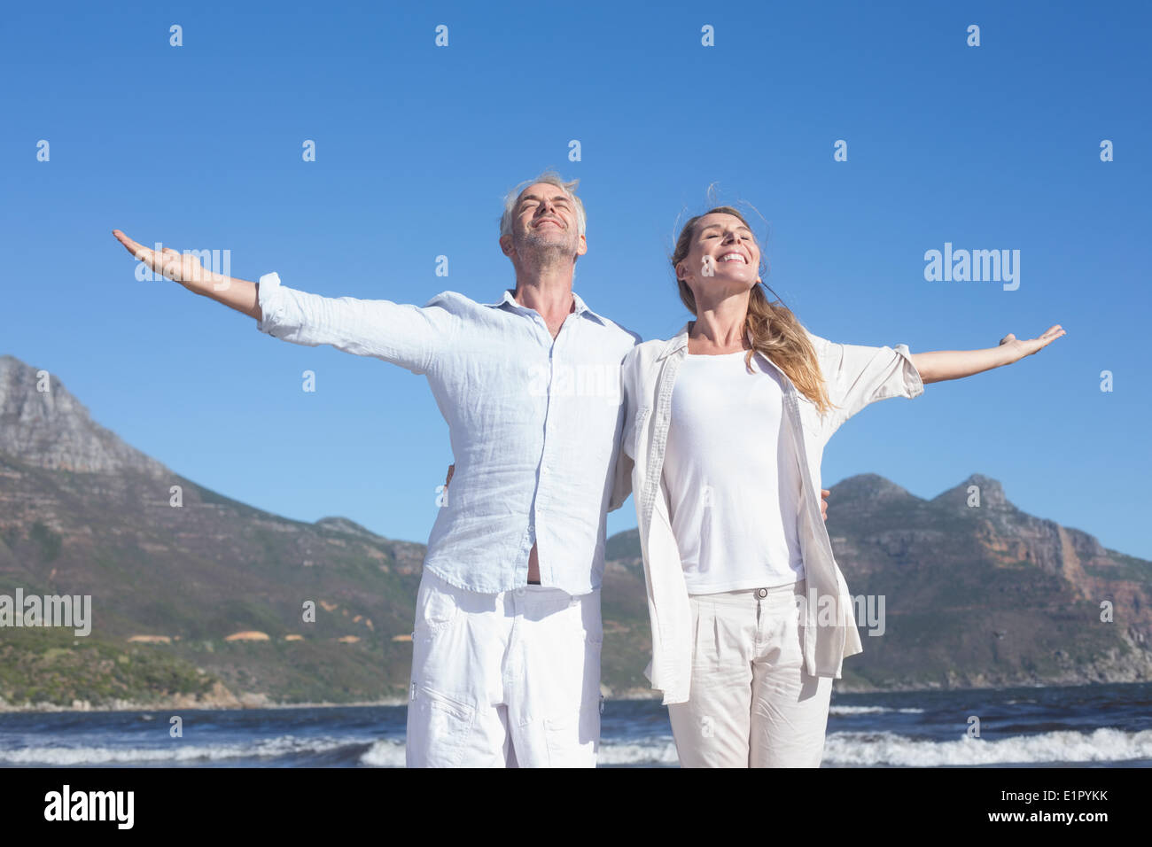 Happy couple standing with arms outstretched at the beach Stock Photo ...