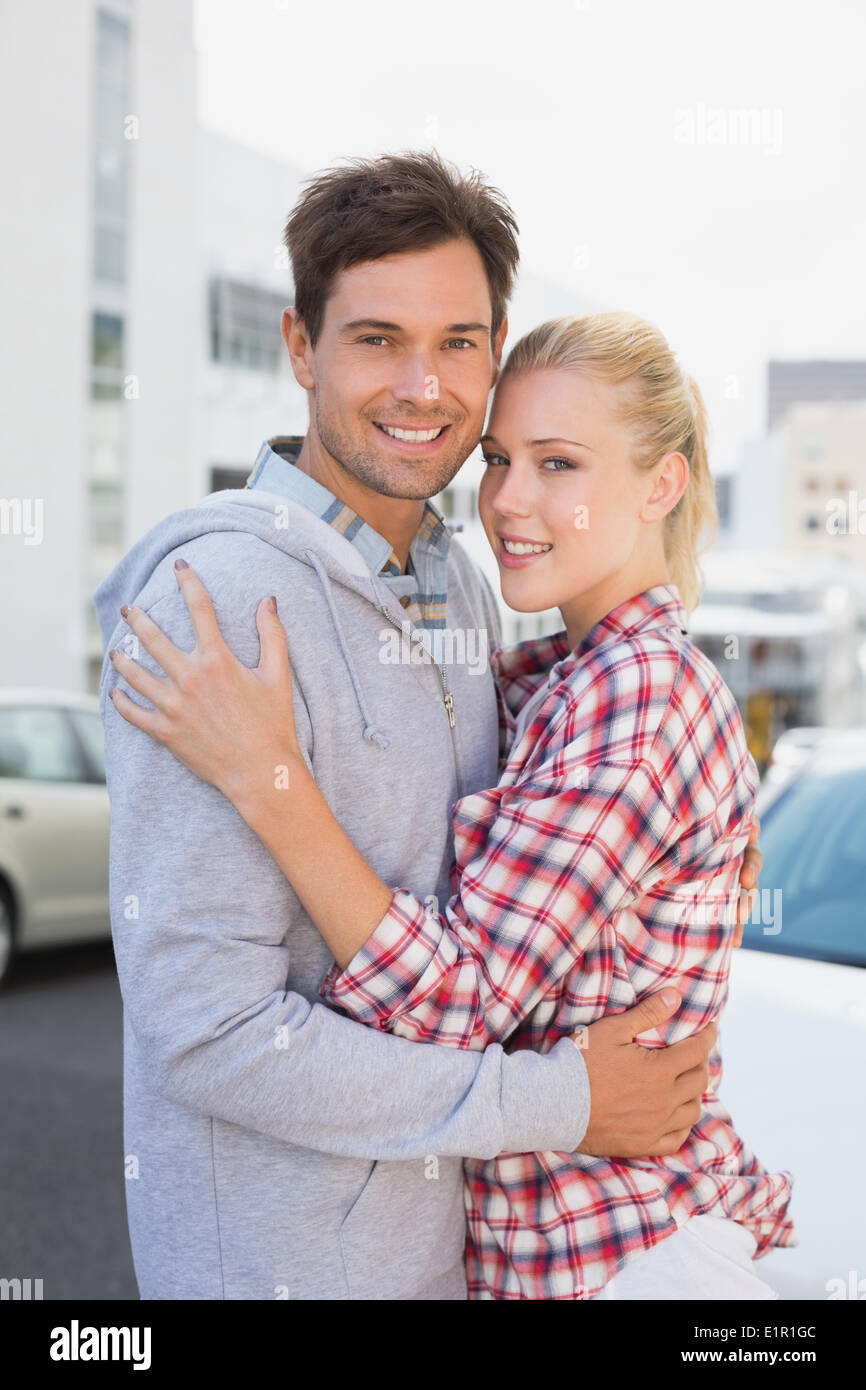 Hip young couple hugging smiling at camera Stock Photo - Alamy