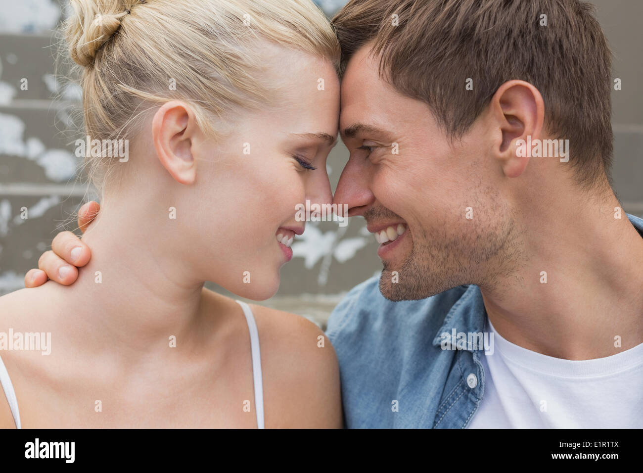 Hip young couple sitting on steps smiling at each other Stock Photo - Alamy