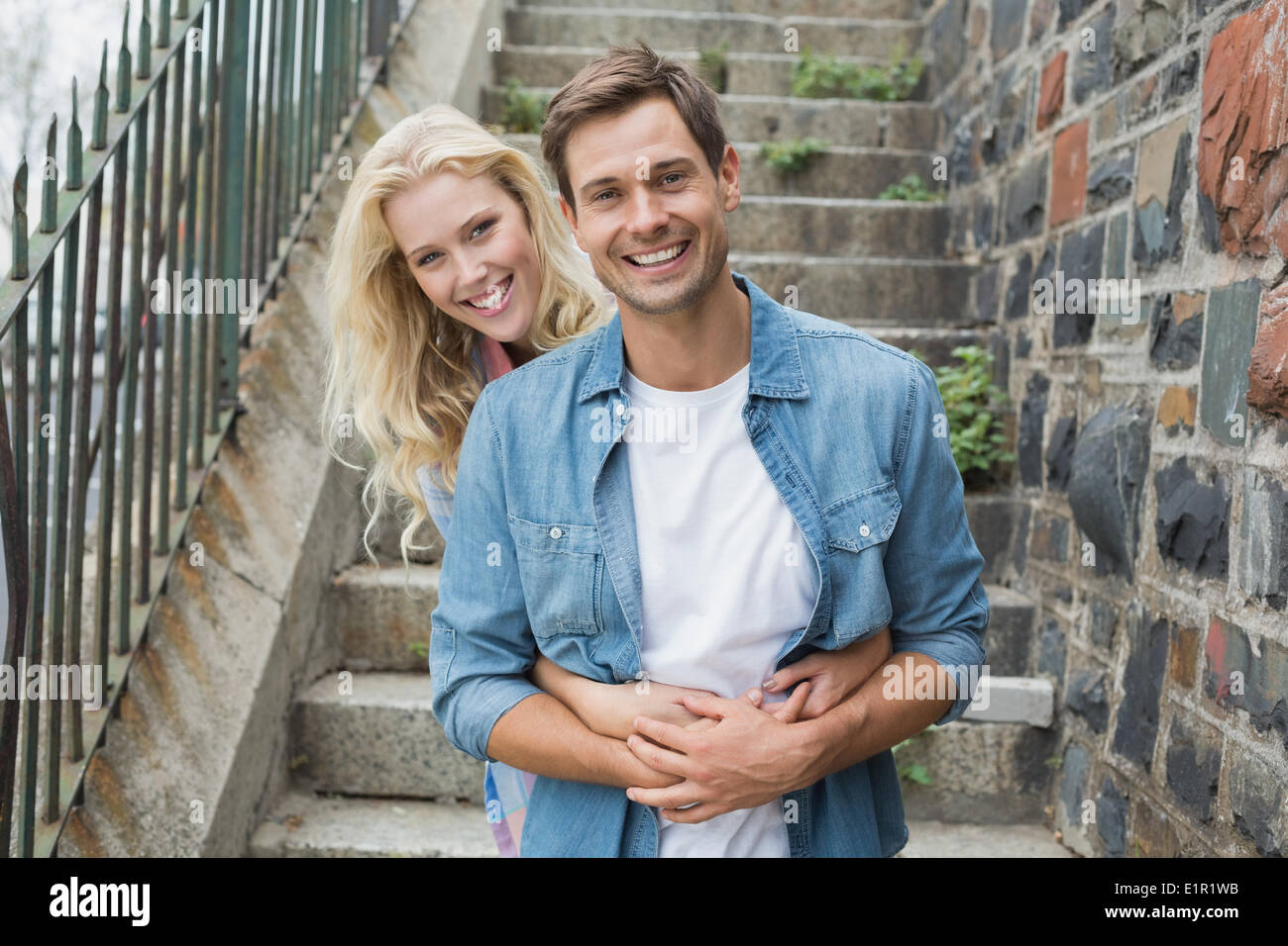 Hip young couple sitting on steps smiling at camera Stock Photo - Alamy