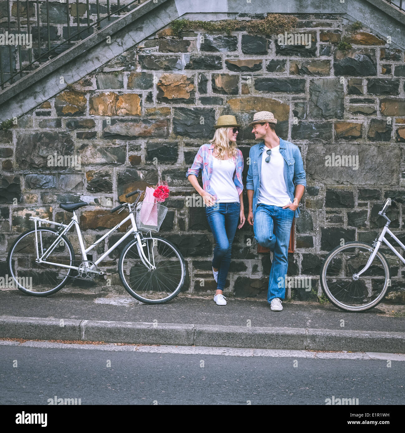 Hip young couple standing by brick wall with their bikes Stock Photo ...