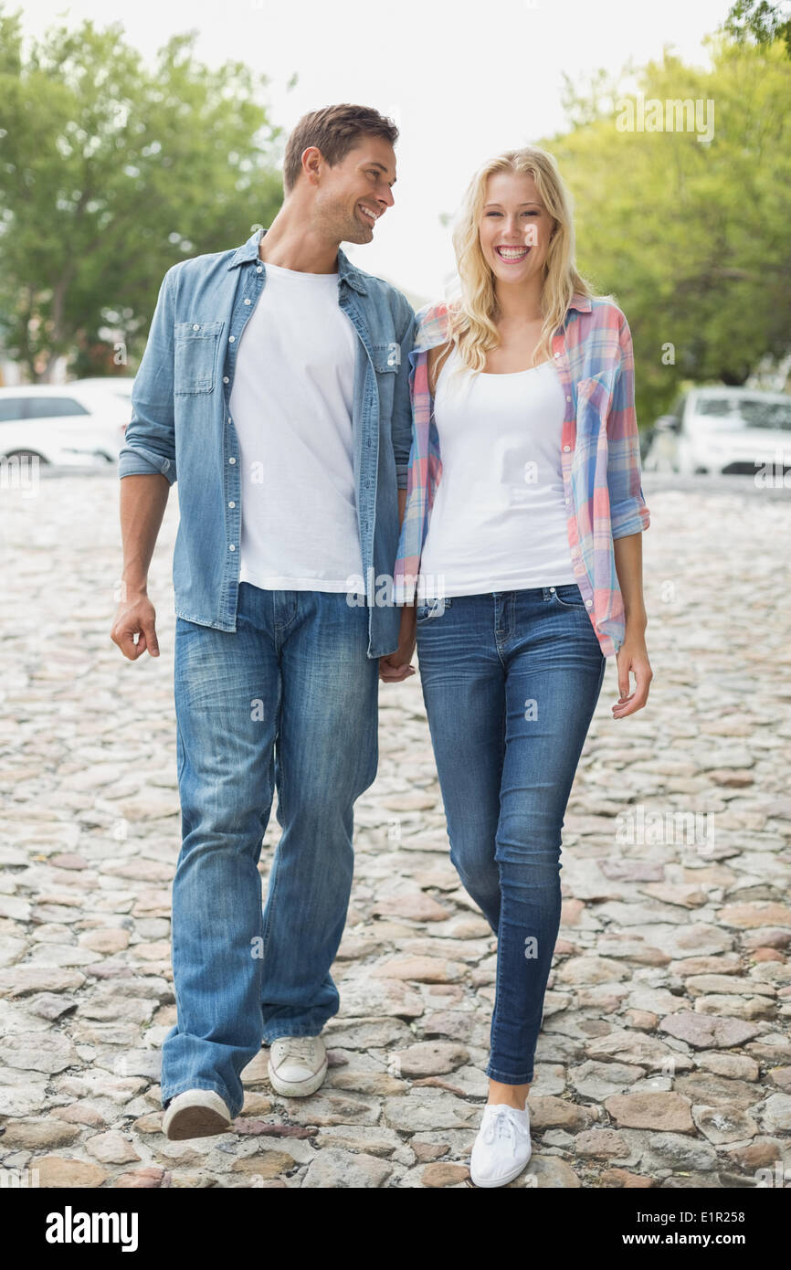 Hip young couple walking holding hands Stock Photo - Alamy