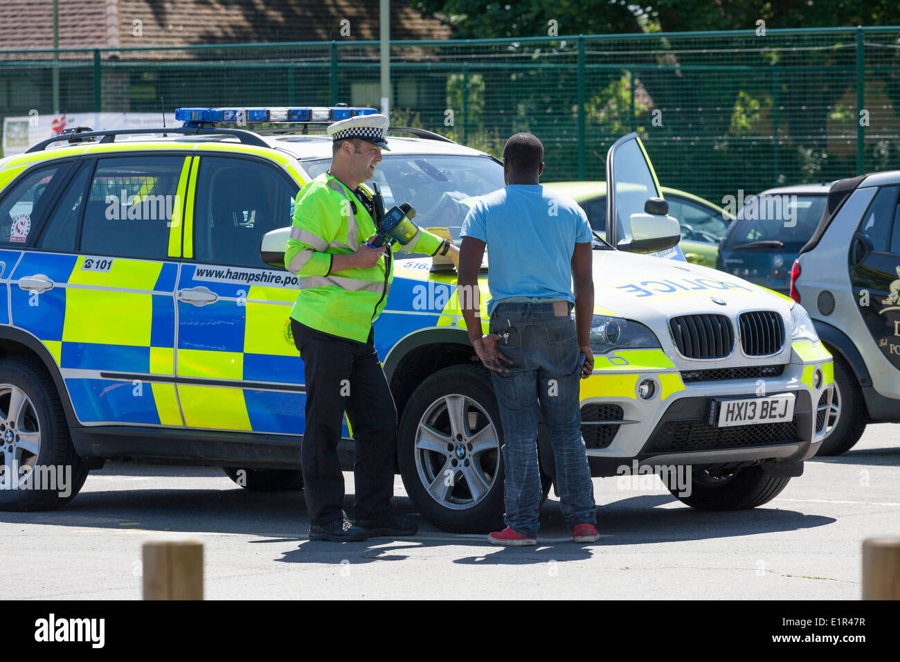 Police officer talking to black man by police car Stock Photo - Alamy