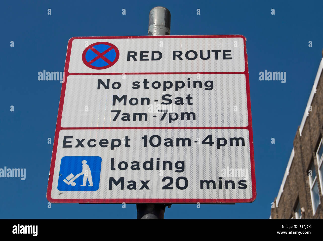 british red route road sign giving times when no stopping is allowed ...