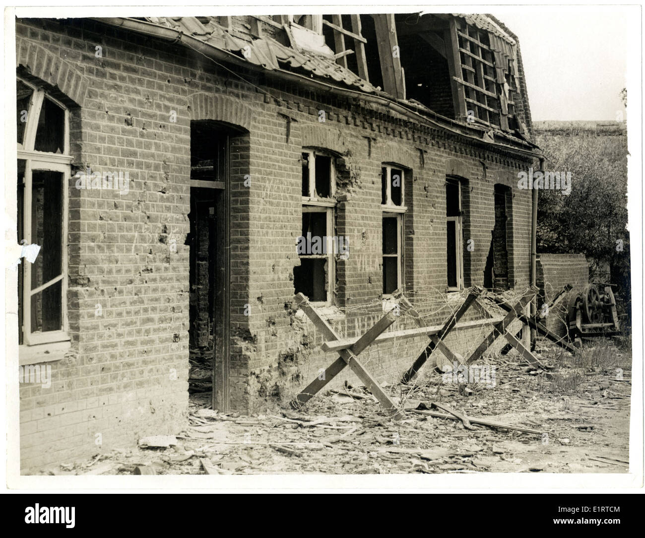 The image shows a war-torn house surrounded by barbed wire, captured ...