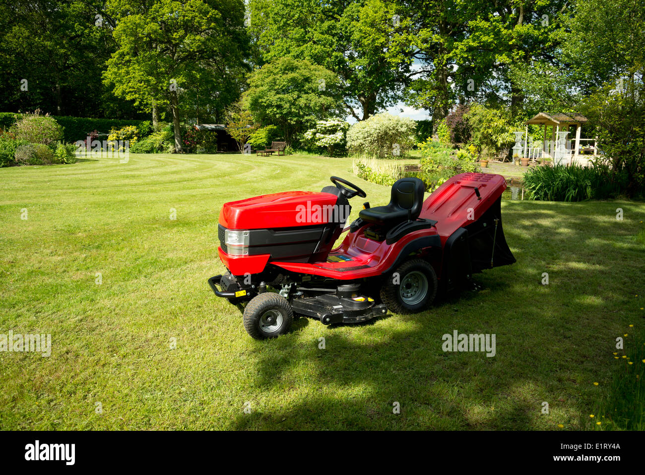 Red garden tractor, or ride on mower, in an verdant garden Stock Photo ...