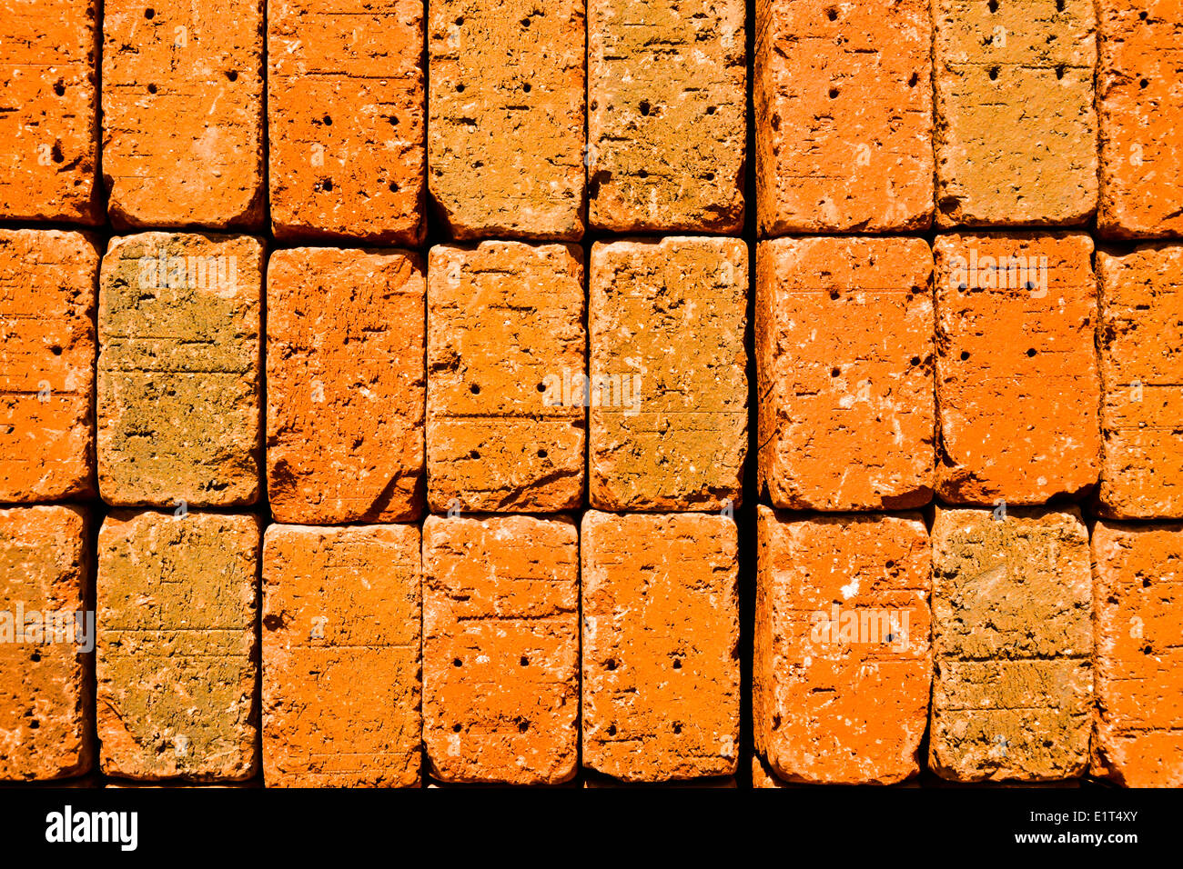 A close up detail of a stack of red bricks showing textures of distress ...