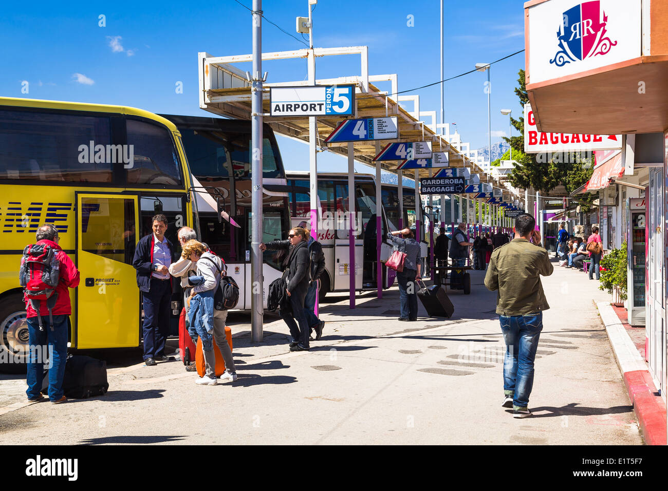 Tourists wait to board a coach and load their bags at the bus terminal ...