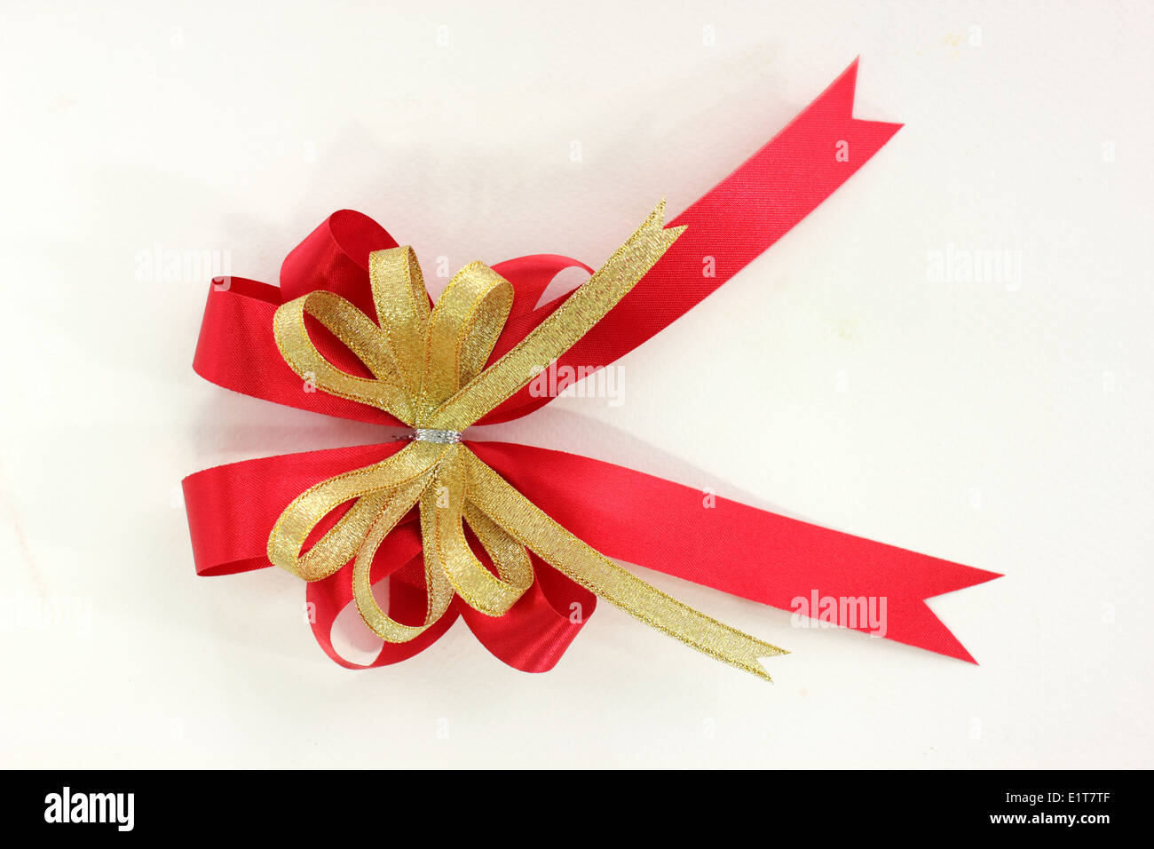 A gold and red ribbon bow on white background Stock Photo - Alamy