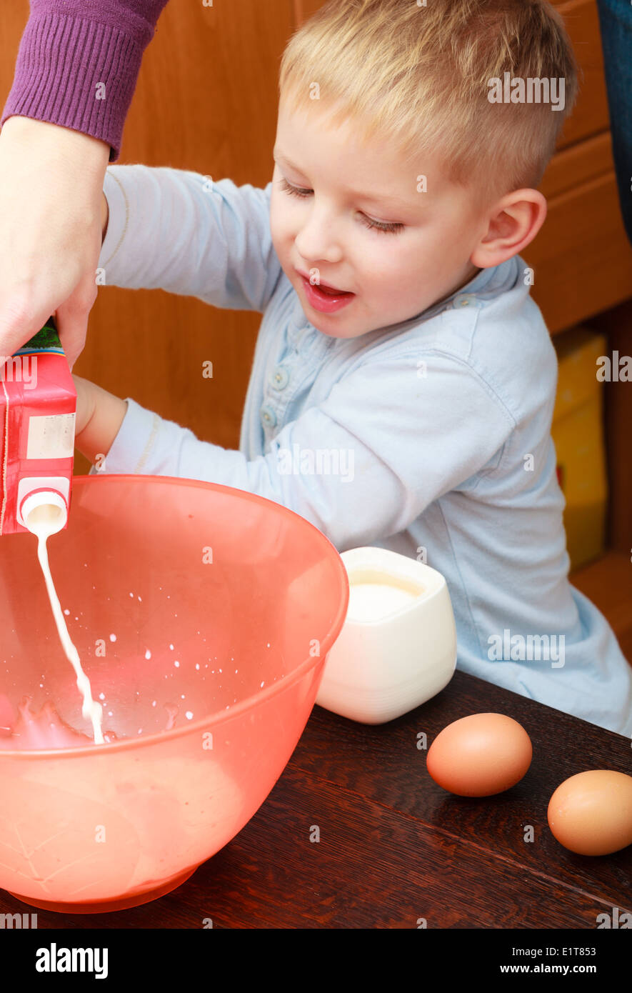 Happy childhood. Boy kid baking cake. Child preschooler pouring mik ...