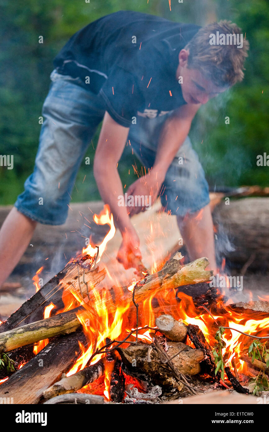Boy sets fire to logs in a campfire Stock Photo - Alamy