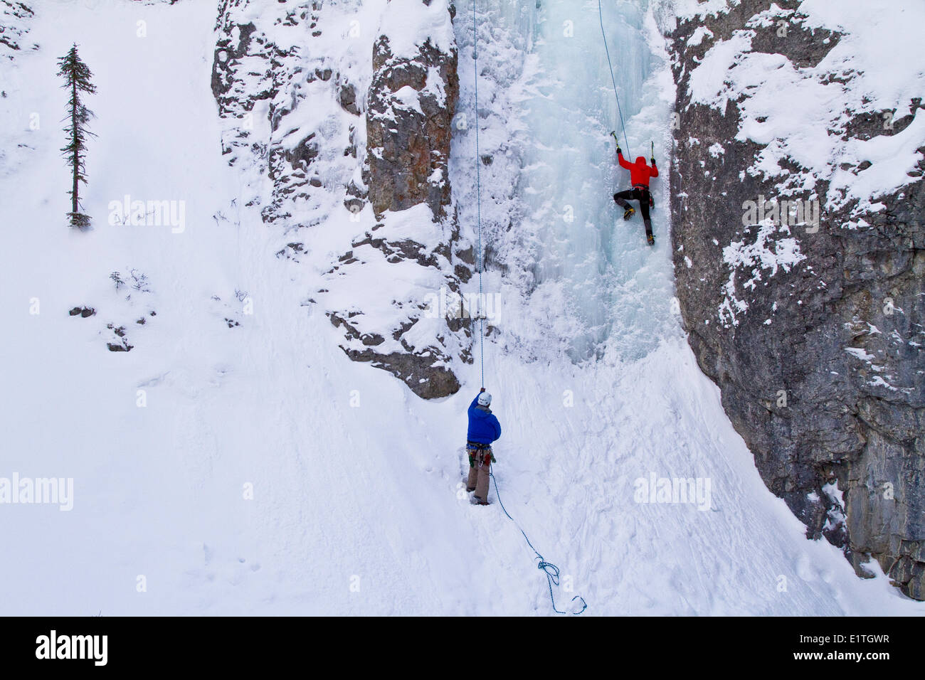 Young man ice-climbing while other man belays him in Banff National ...
