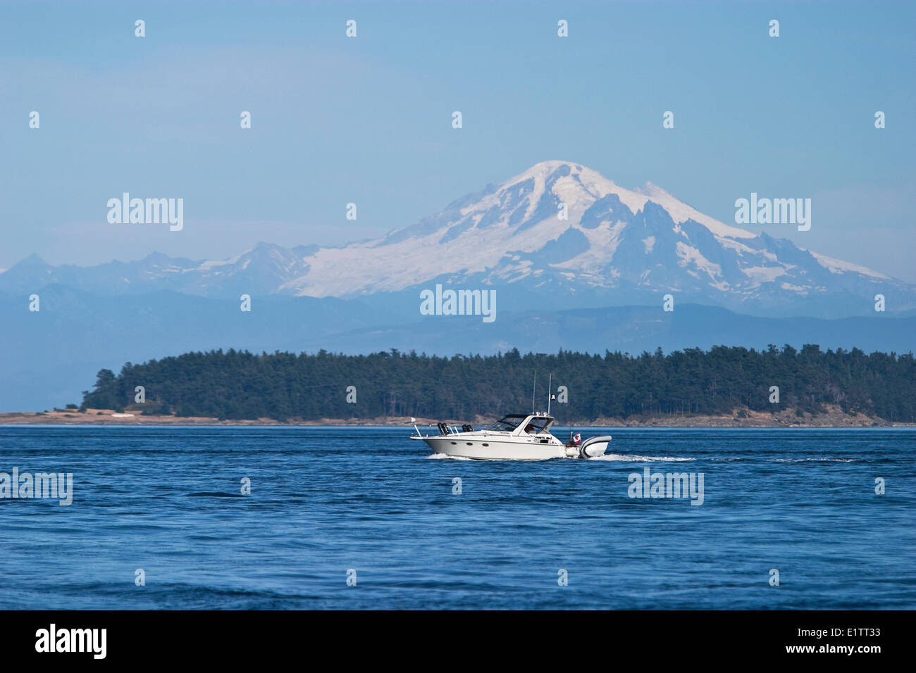 A boat cruises through waters in Haro Strait with Mt. Baker in the ...